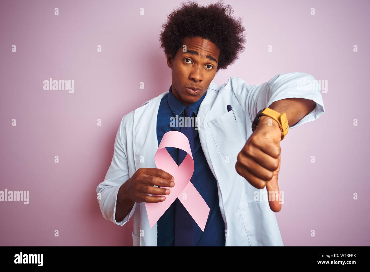 Young afro american doctor man holding cancer ribbon standing over ...