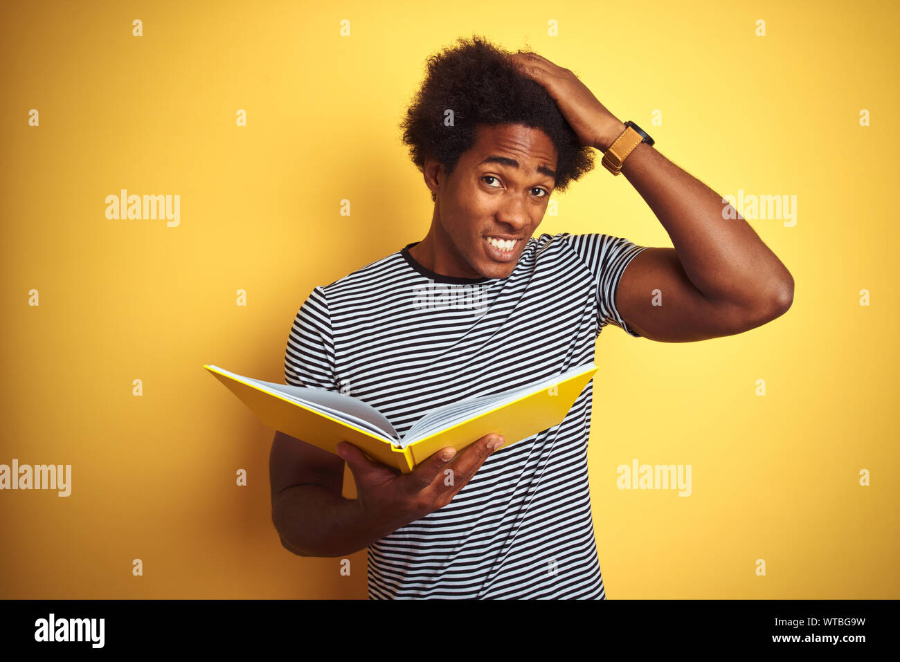 Afro american student man reading book standing over isolated yellow ...