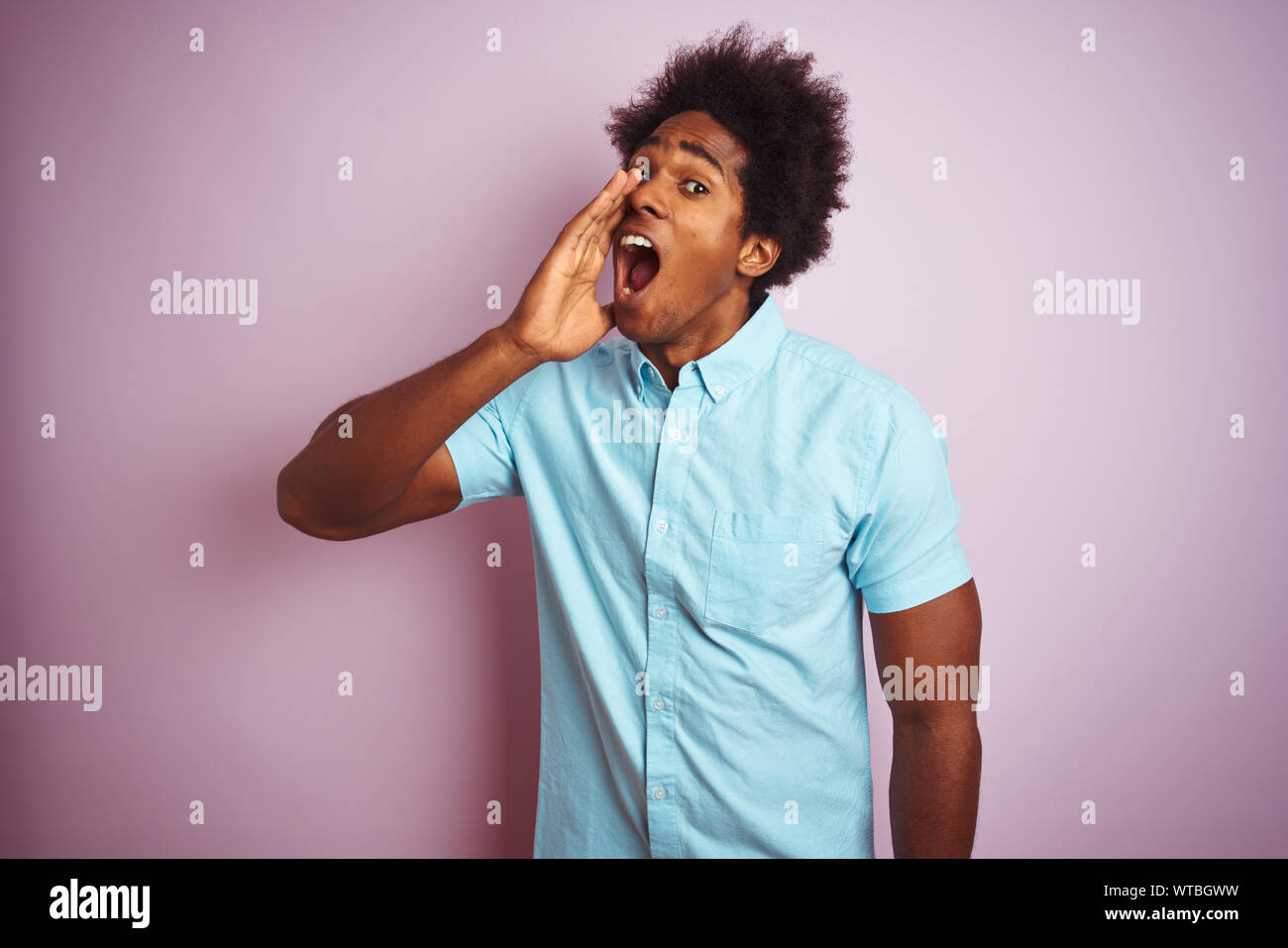 Young american man with afro hair wearing blue shirt standing over ...