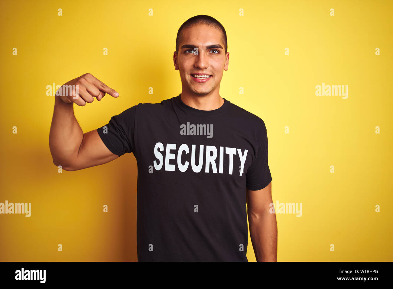 Young safeguard man with security t-shirt over yellow isolated ...