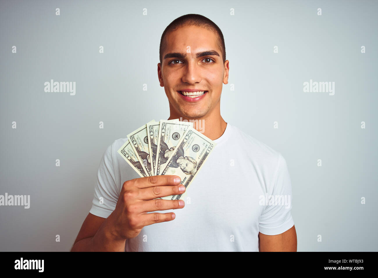 Young handsome man holding dollars over white isolated background with ...