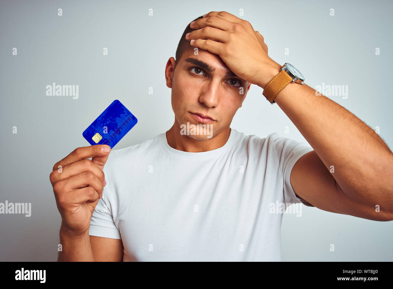 Young handsome man holding credit card over white isolated background ...