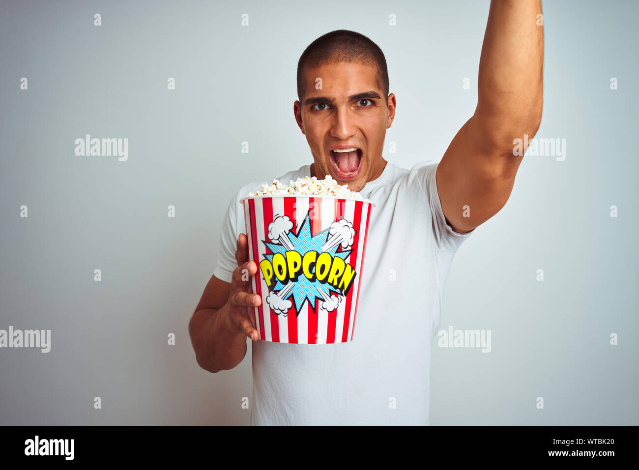 Young handsome man eating popcorn over white isolated background ...