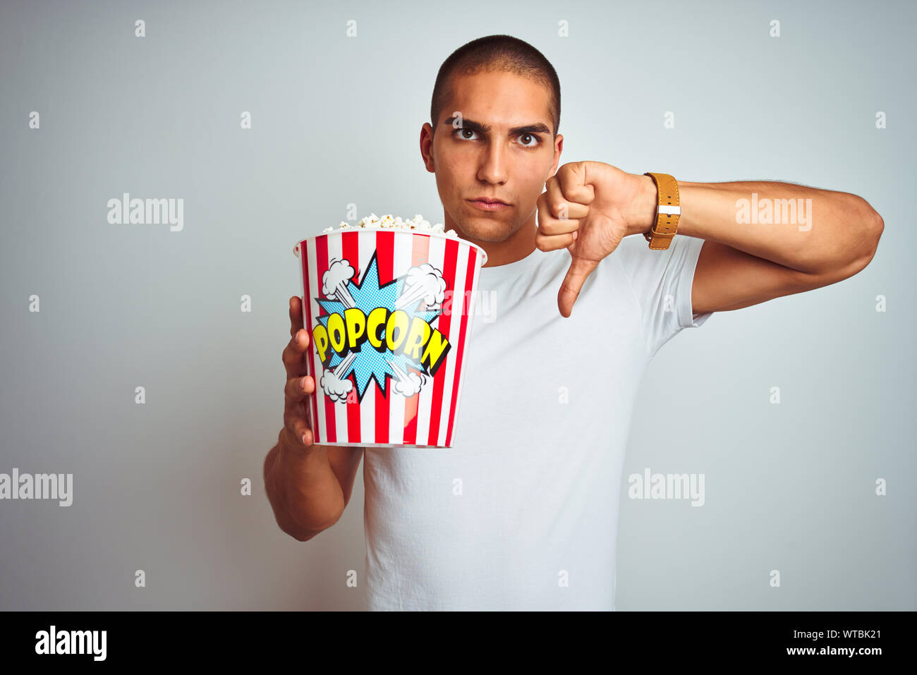 Young handsome man eating popcorn over white isolated background with ...