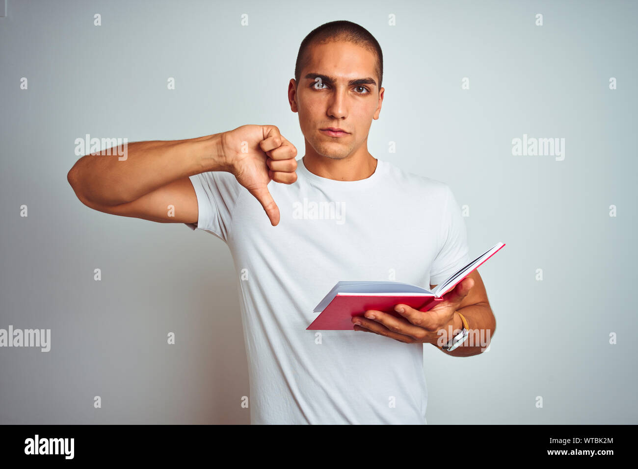 Young handsome man reading red book over white isolated background with ...