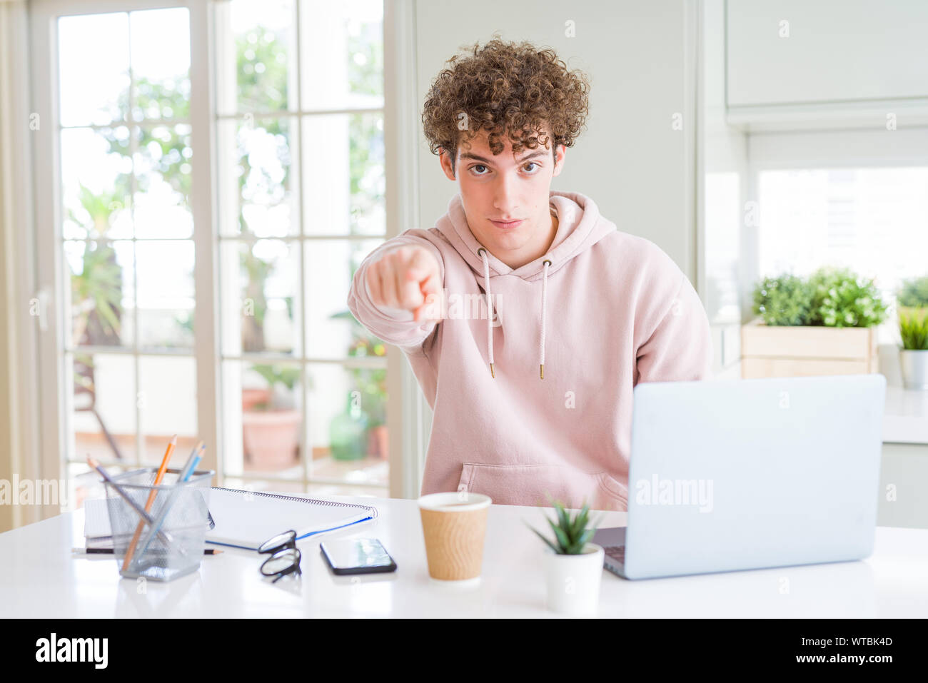Young student man working and studying using computer laptop pointing ...