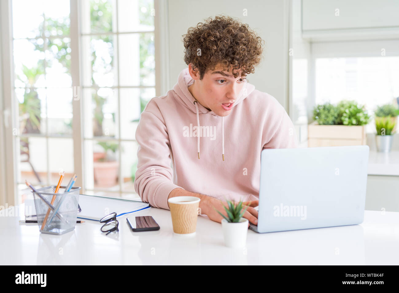 Young student man working and studying using computer laptop scared in ...