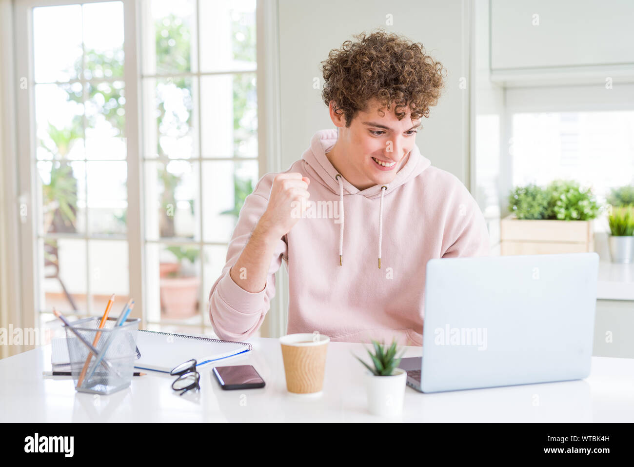 Young student man working and studying using computer laptop screaming ...