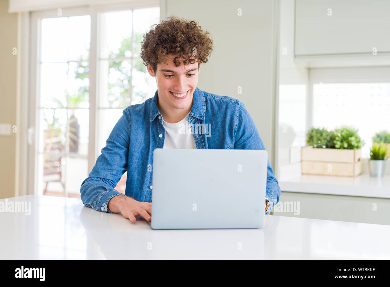 Young man using computer laptop with a happy face standing and smiling ...