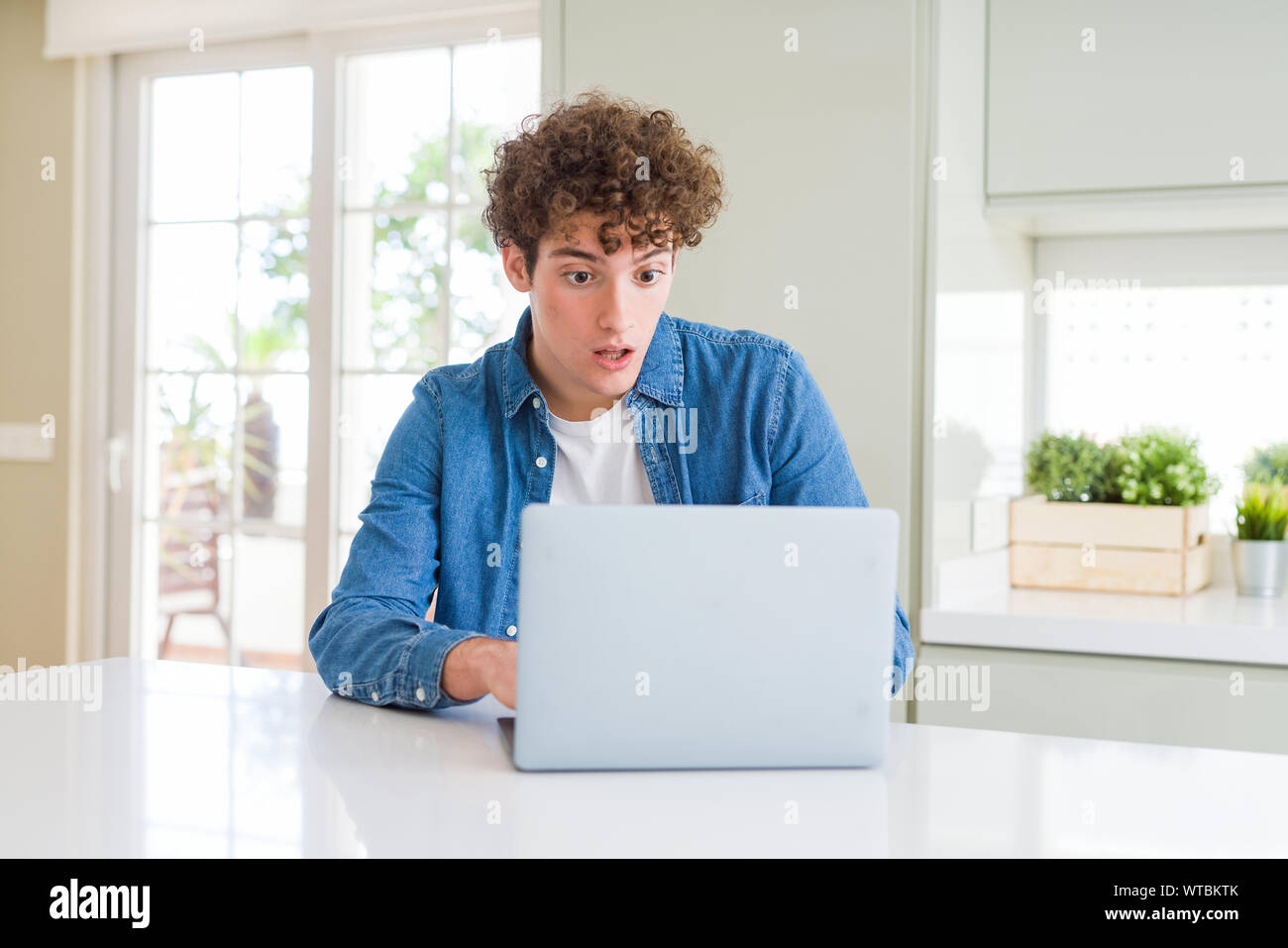 Young man using computer laptop scared in shock with a surprise face ...