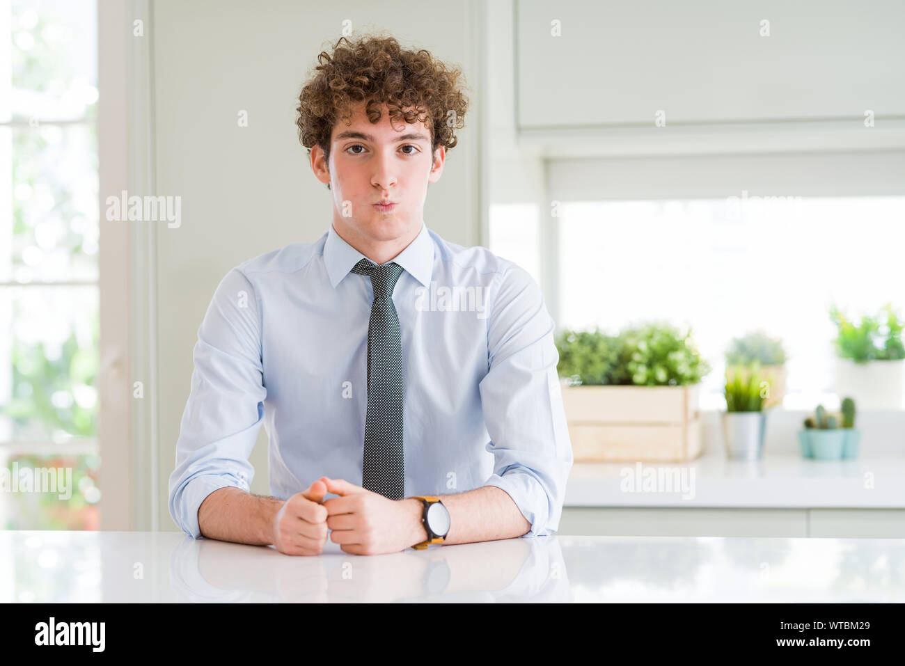Young business man wearing a tie puffing cheeks with funny face. Mouth ...