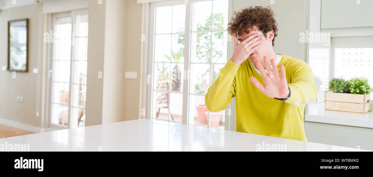 Wide angle shot of young handsome man at home covering eyes with hands ...