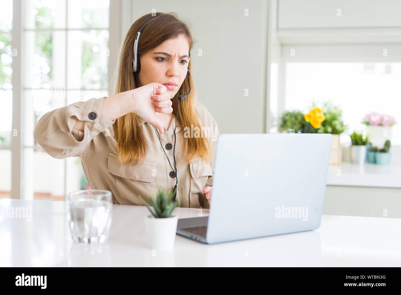 Beautiful young operator woman working with laptop and wearing headseat ...