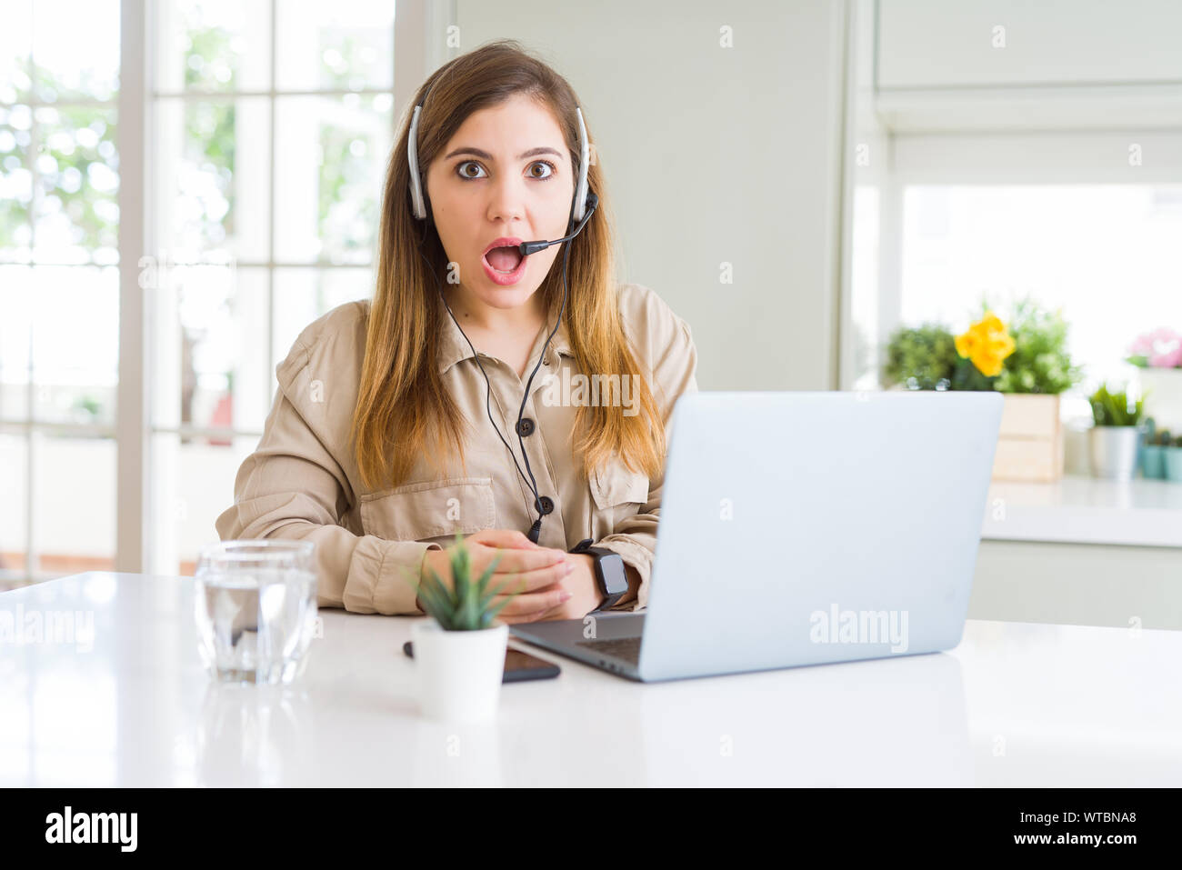 Beautiful young operator woman working with laptop and wearing headseat ...