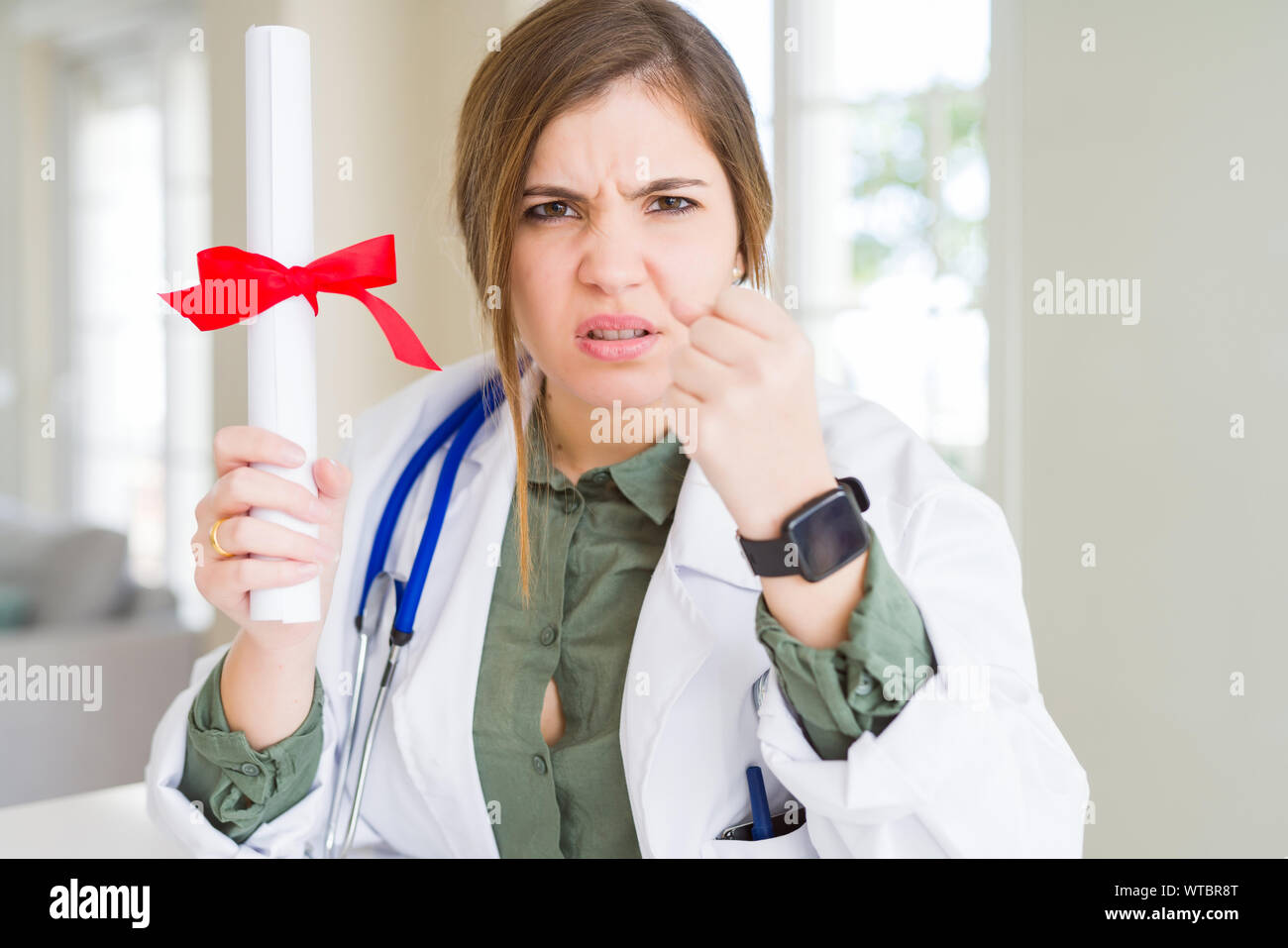 Beautiful young doctor woman holding degree annoyed and frustrated ...