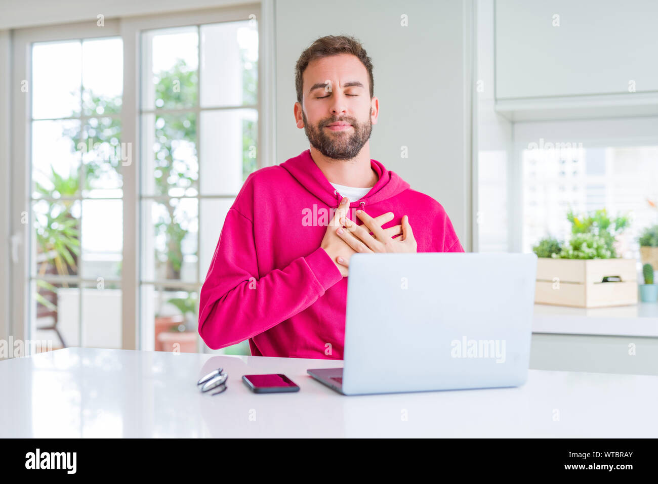 Handsome man working using computer laptop smiling with hands on chest ...