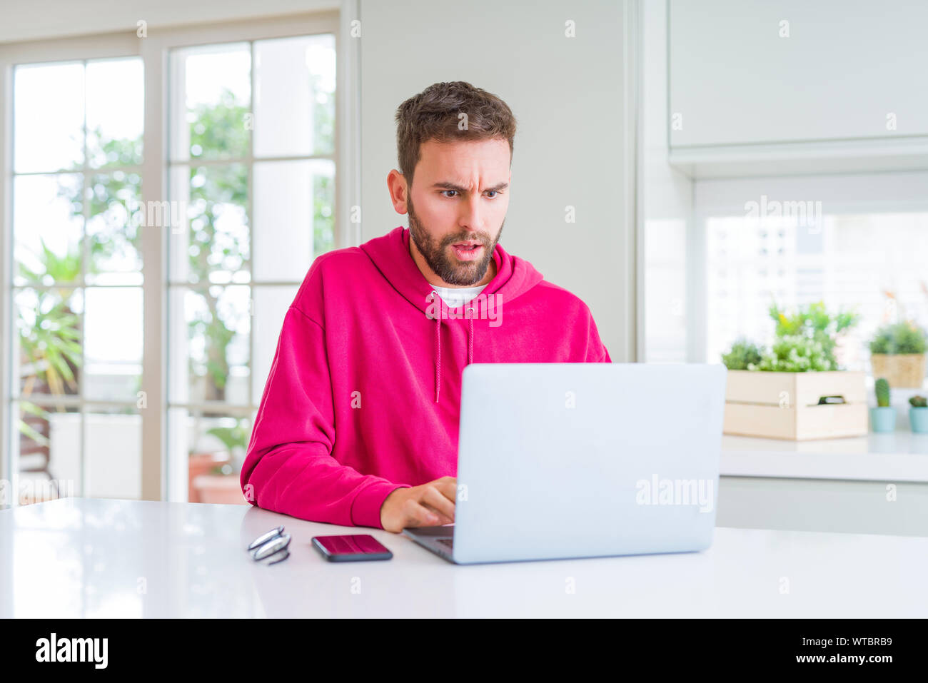 Handsome man working using computer laptop afraid and shocked with ...