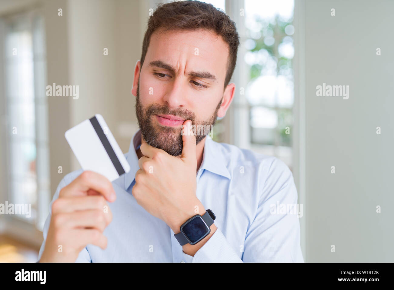 Handsome business man holding credit card serious face thinking about ...