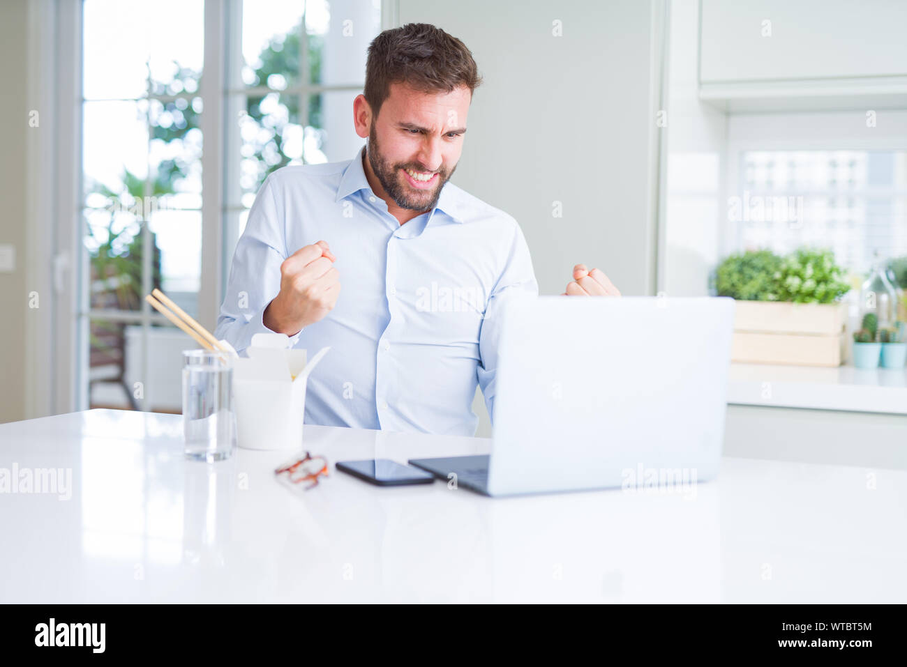 Business man eating take away asian noodles food while working using ...