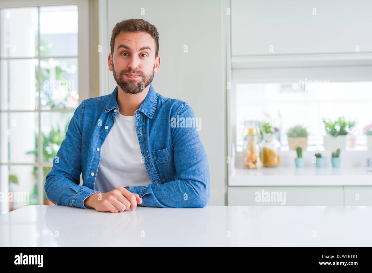 Handsome man at home puffing cheeks with funny face. Mouth inflated ...