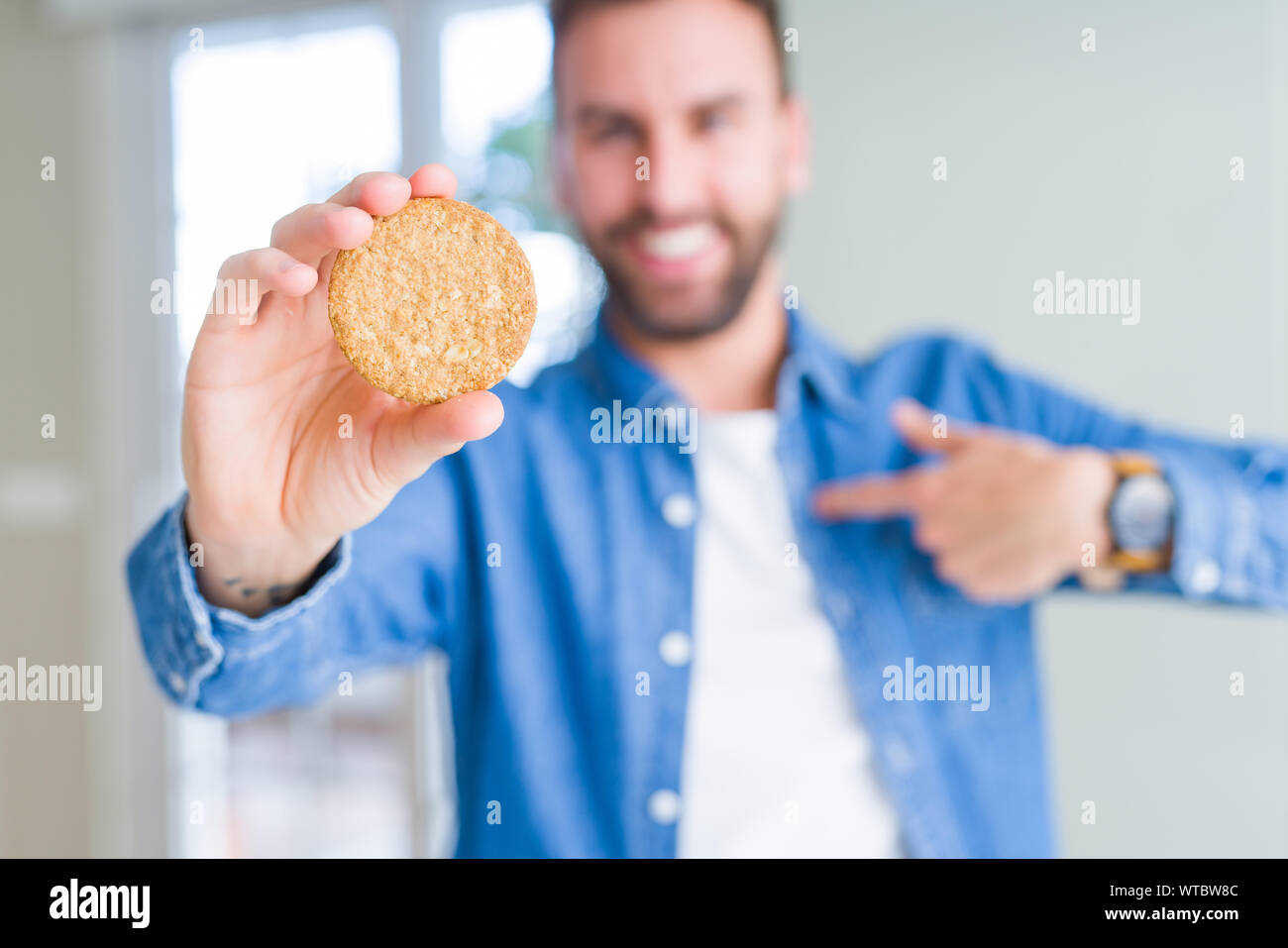 Handsome man eating healthy whole grain biscuit with surprise face ...