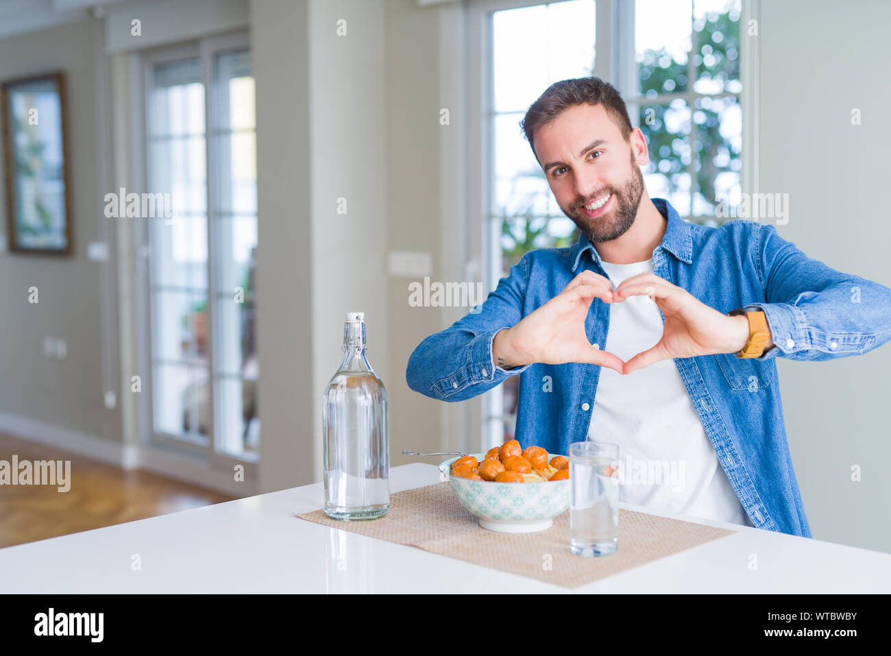 Handsome man eating pasta with meatballs and tomato sauce at home ...