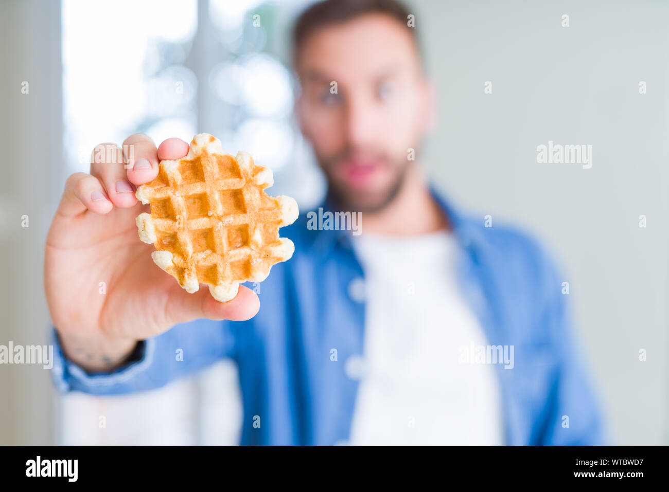 Handsome man eating sweet Belgian pancakes scared in shock with a ...