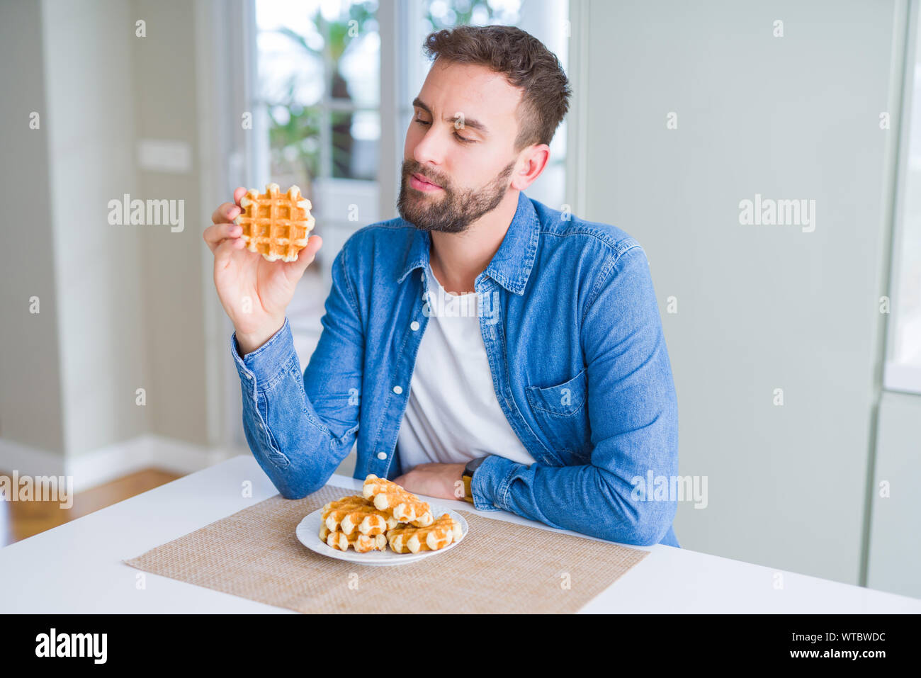 Handsome man eating sweet Belgian pancakes with a confident expression ...
