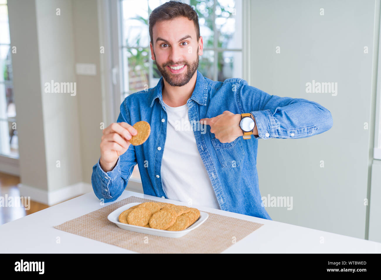 Handsome man eating healthy whole grain biscuit with surprise face ...