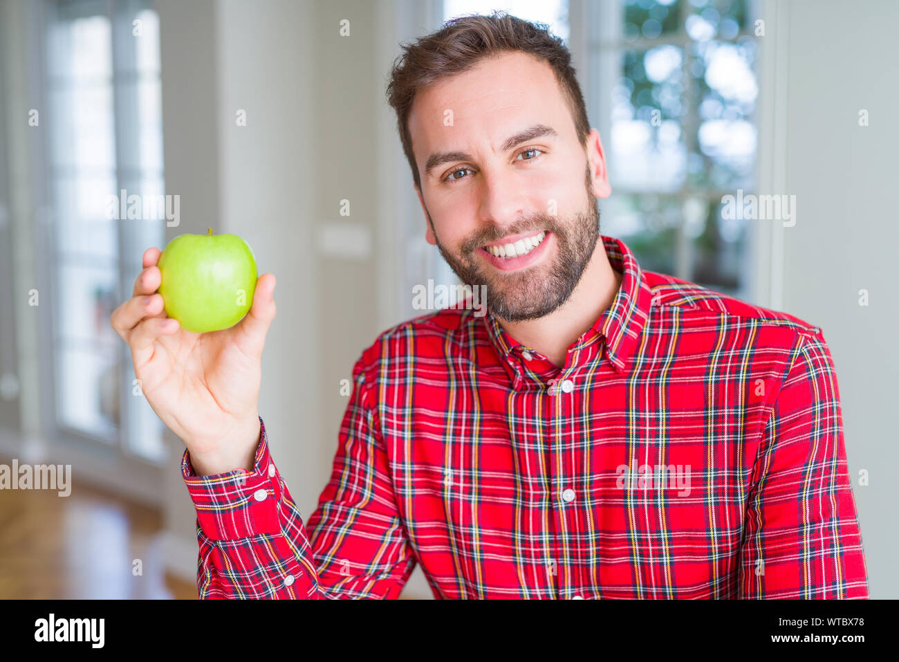 Handsome man eating fresh healthy green apple with a happy face ...