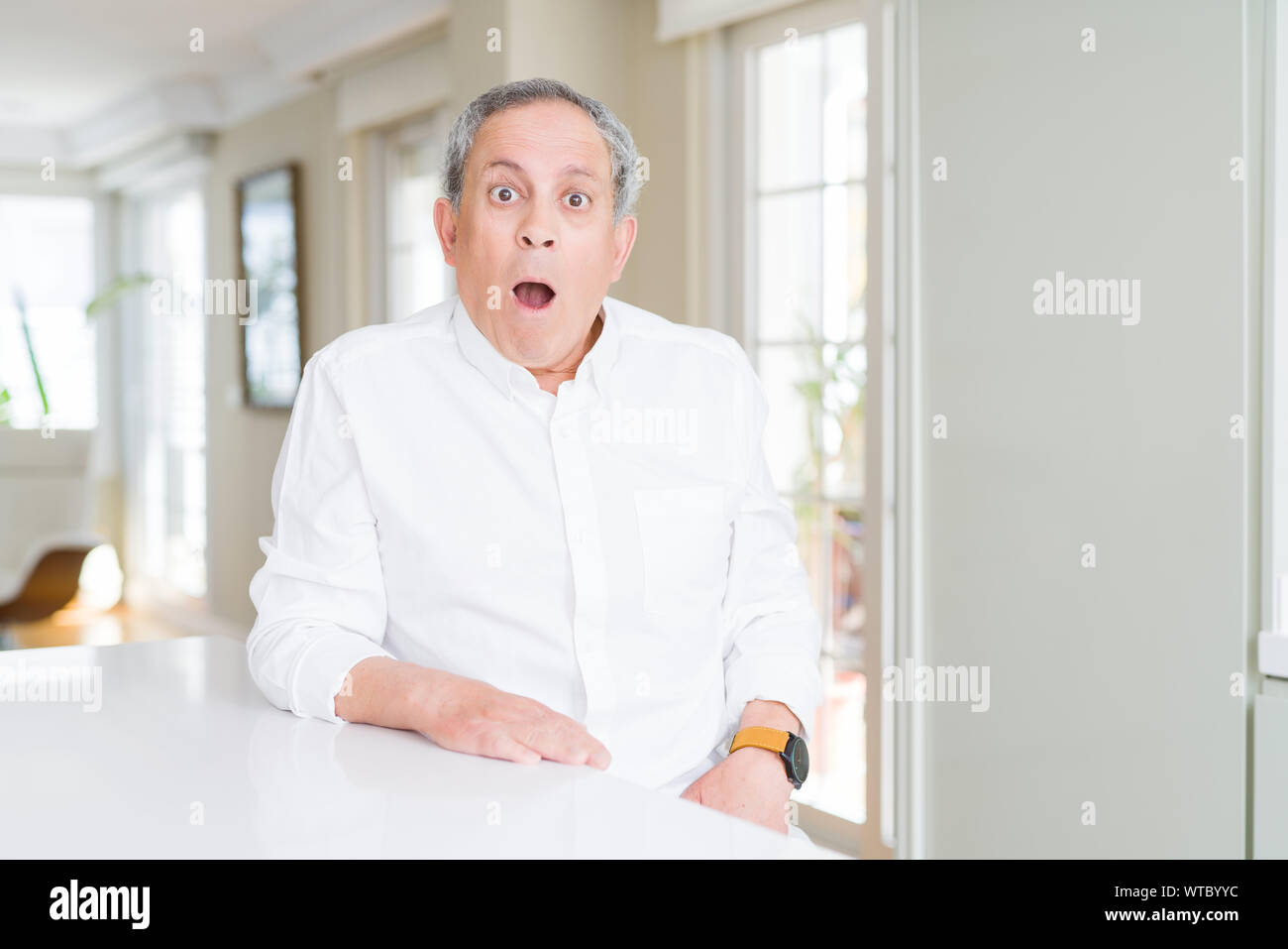 Handsome senior man at home afraid and shocked with surprise expression ...