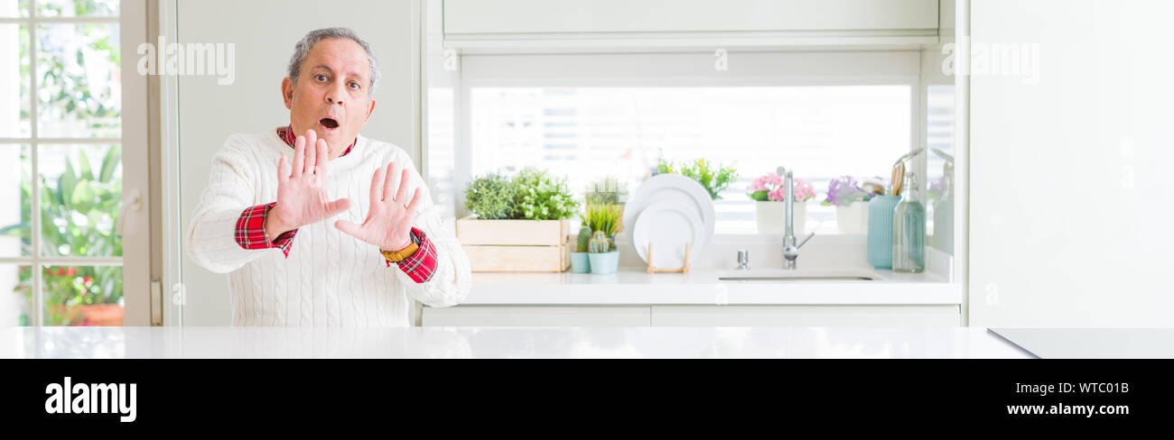 Wide angle perspective of handsome senior man at home afraid and ...
