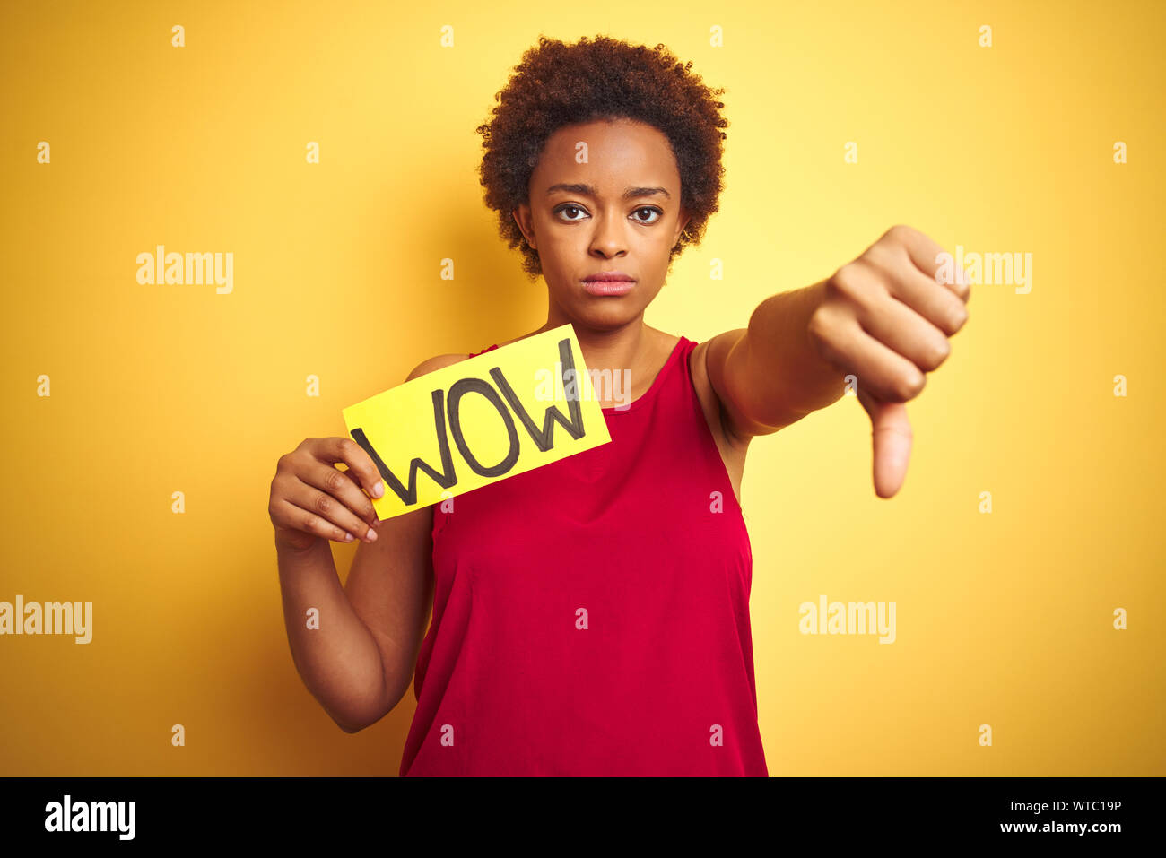 Young african american woman showing wow banner board over yellow ...
