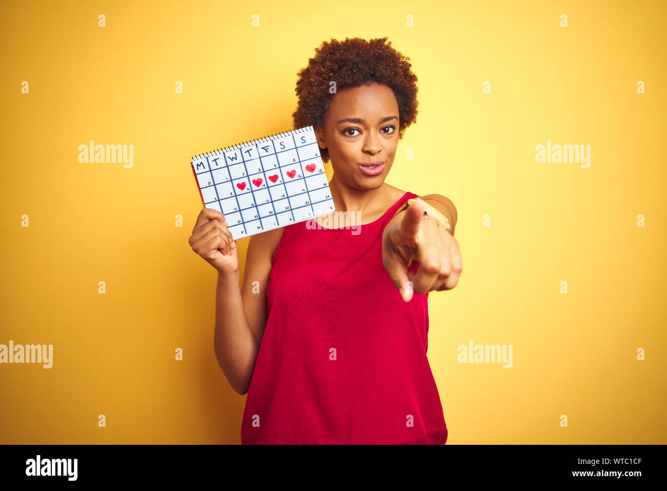 Young african american woman holding menstruation calendar over ...