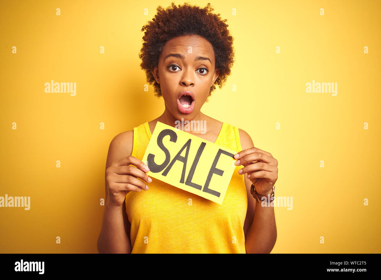 African american woman holding sale board over yellow isolated ...