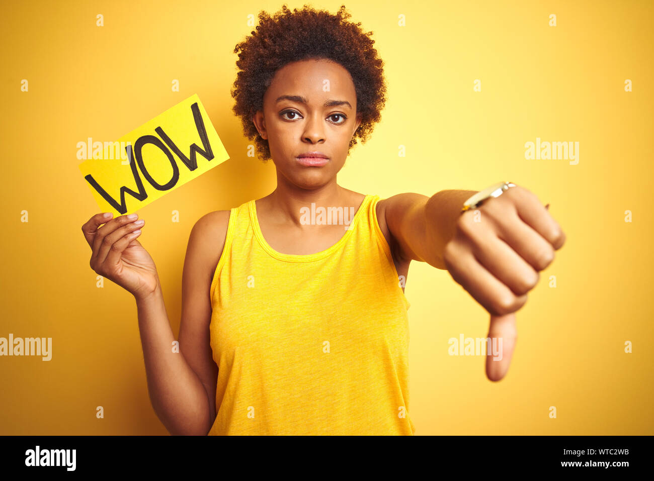 Young african american woman showing wow banner board over yellow ...