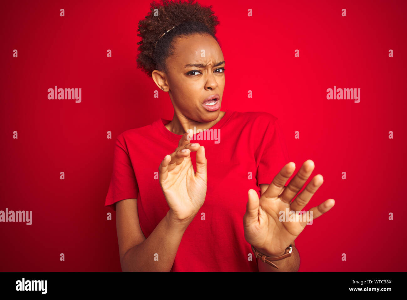 Young beautiful african american woman with afro hair over isolated red ...
