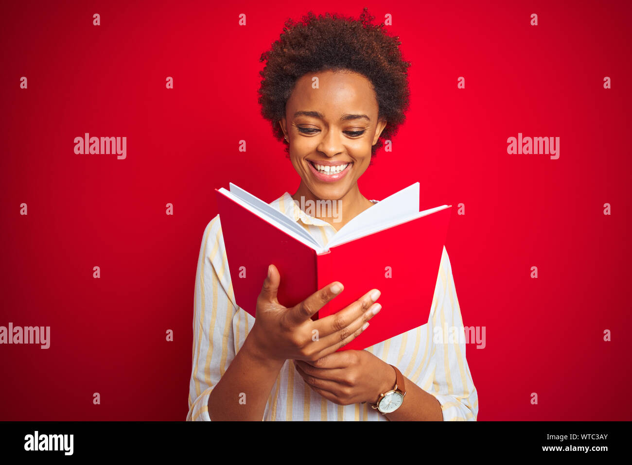 African american woman reading a book over red isolated background with ...