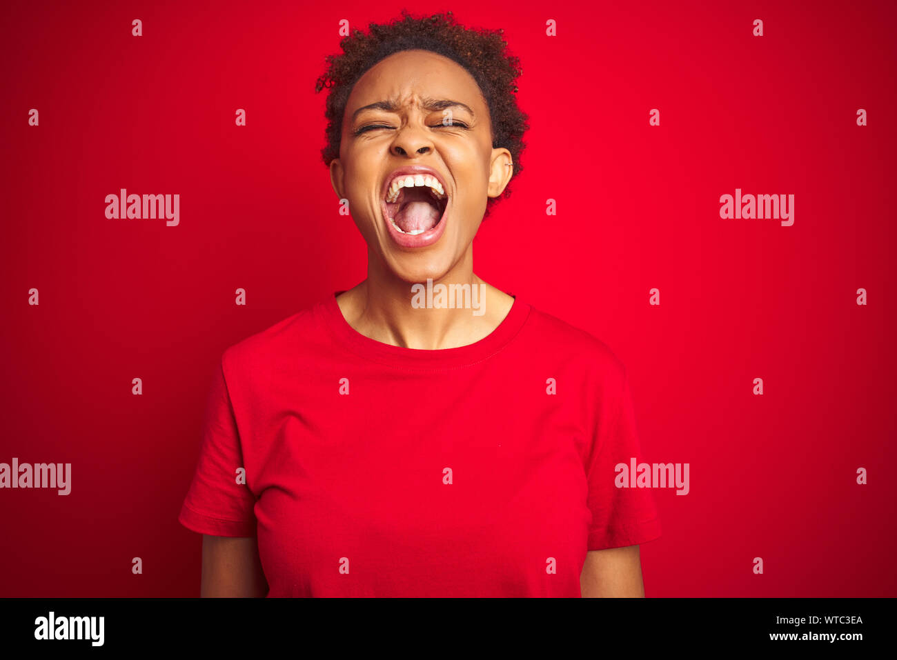 Young beautiful african american woman with afro hair over isolated red ...