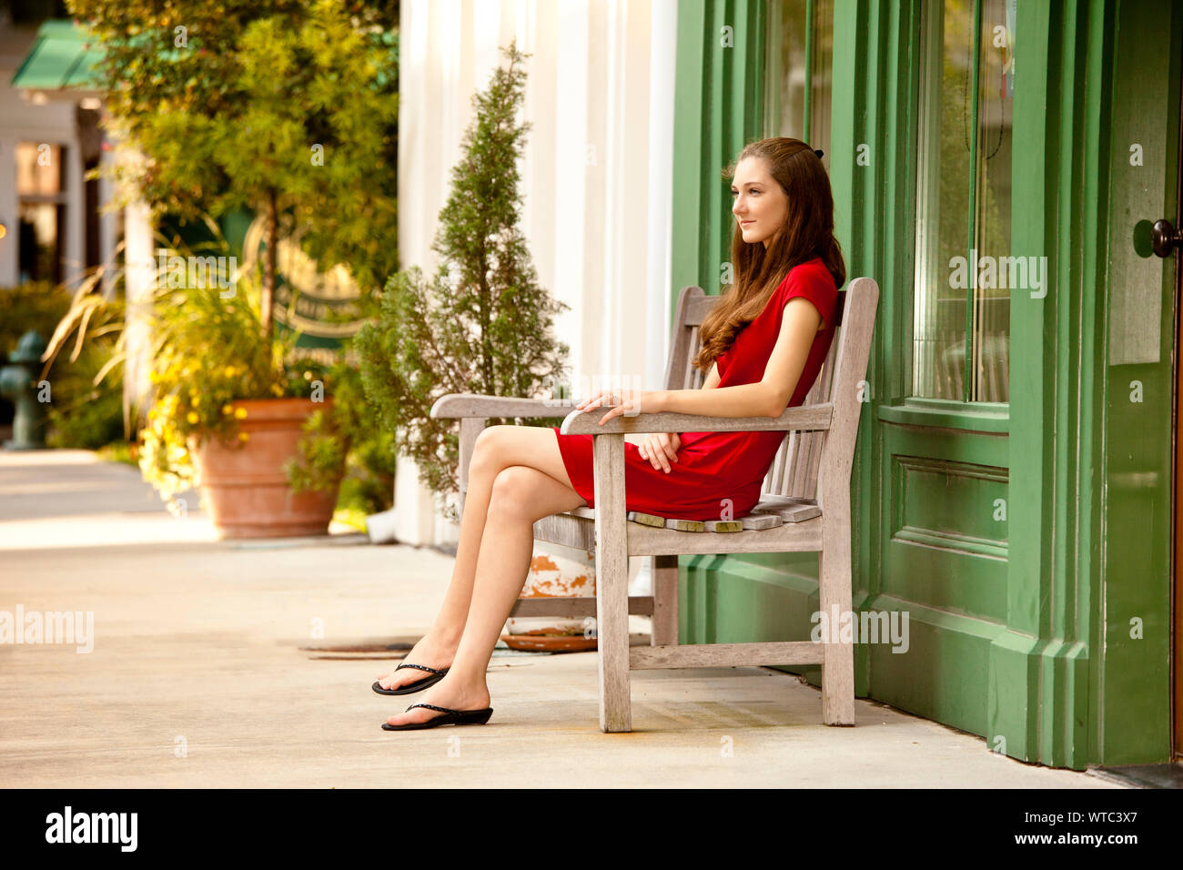 attractive young woman seated outside, full body shot Stock Photo - Alamy
