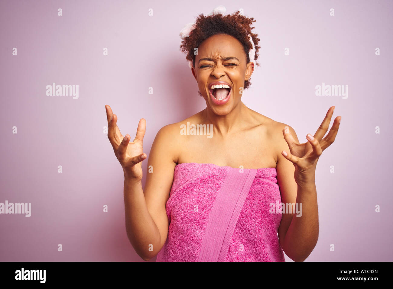 African american woman wearing shower towel after bath over pink ...