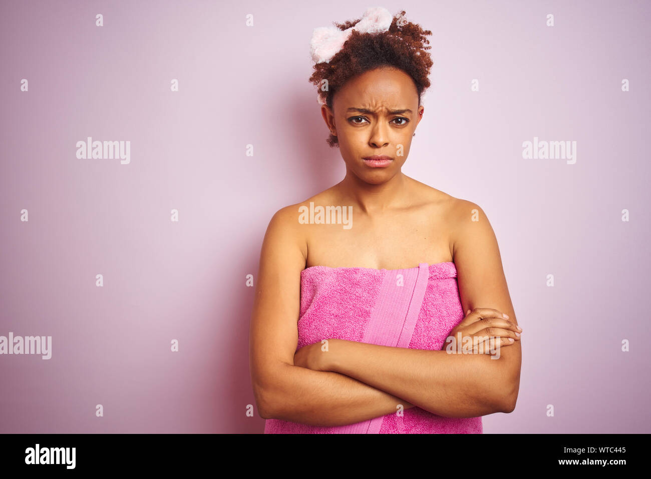 African american woman wearing shower towel after bath over pink ...