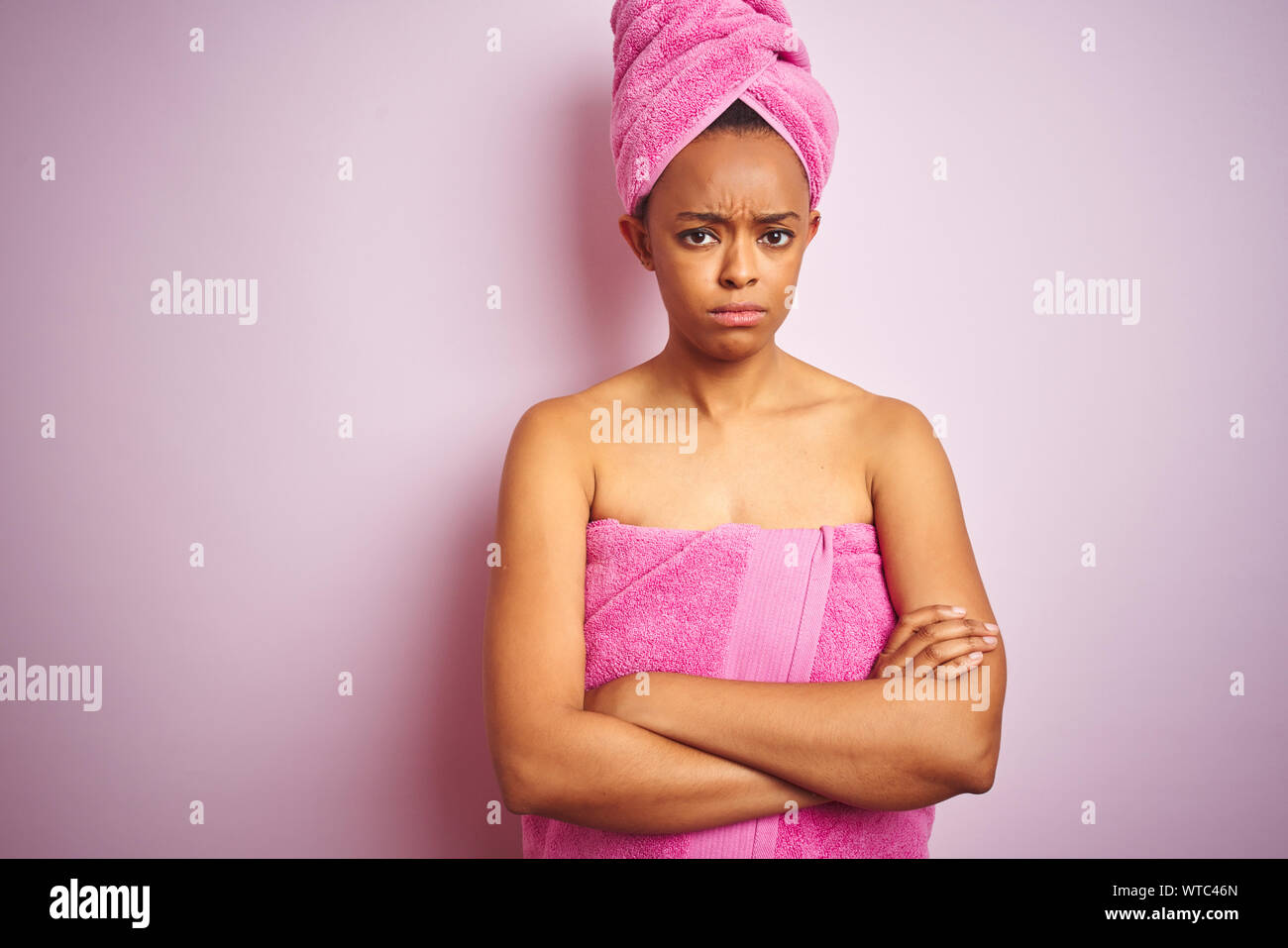 African american woman wearing shower towel after bath over pink ...