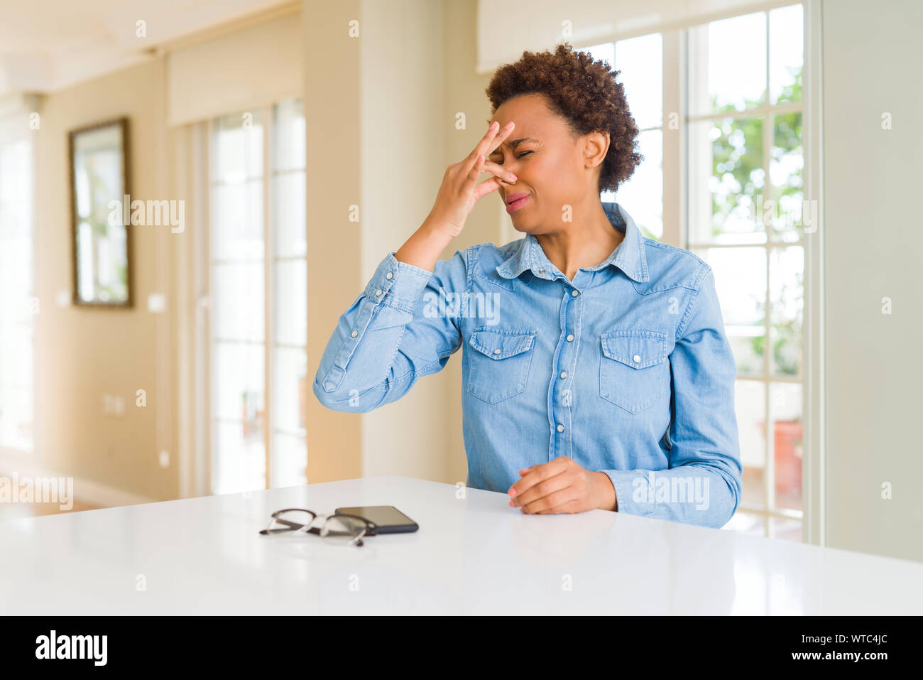 Young beautiful african american woman smelling something stinky and ...