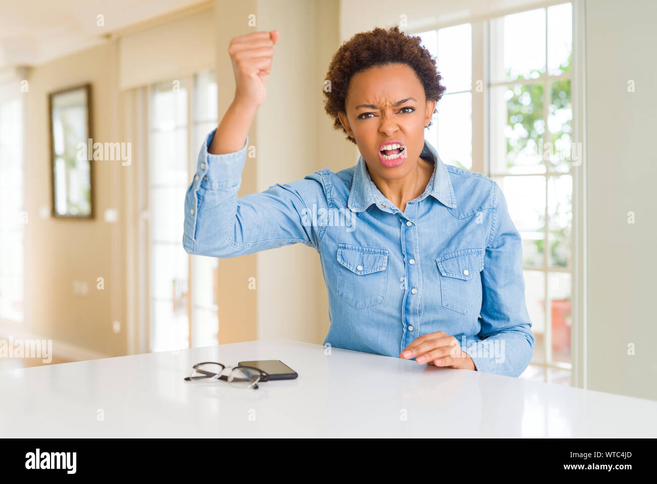 Young beautiful african american woman angry and mad raising fist ...