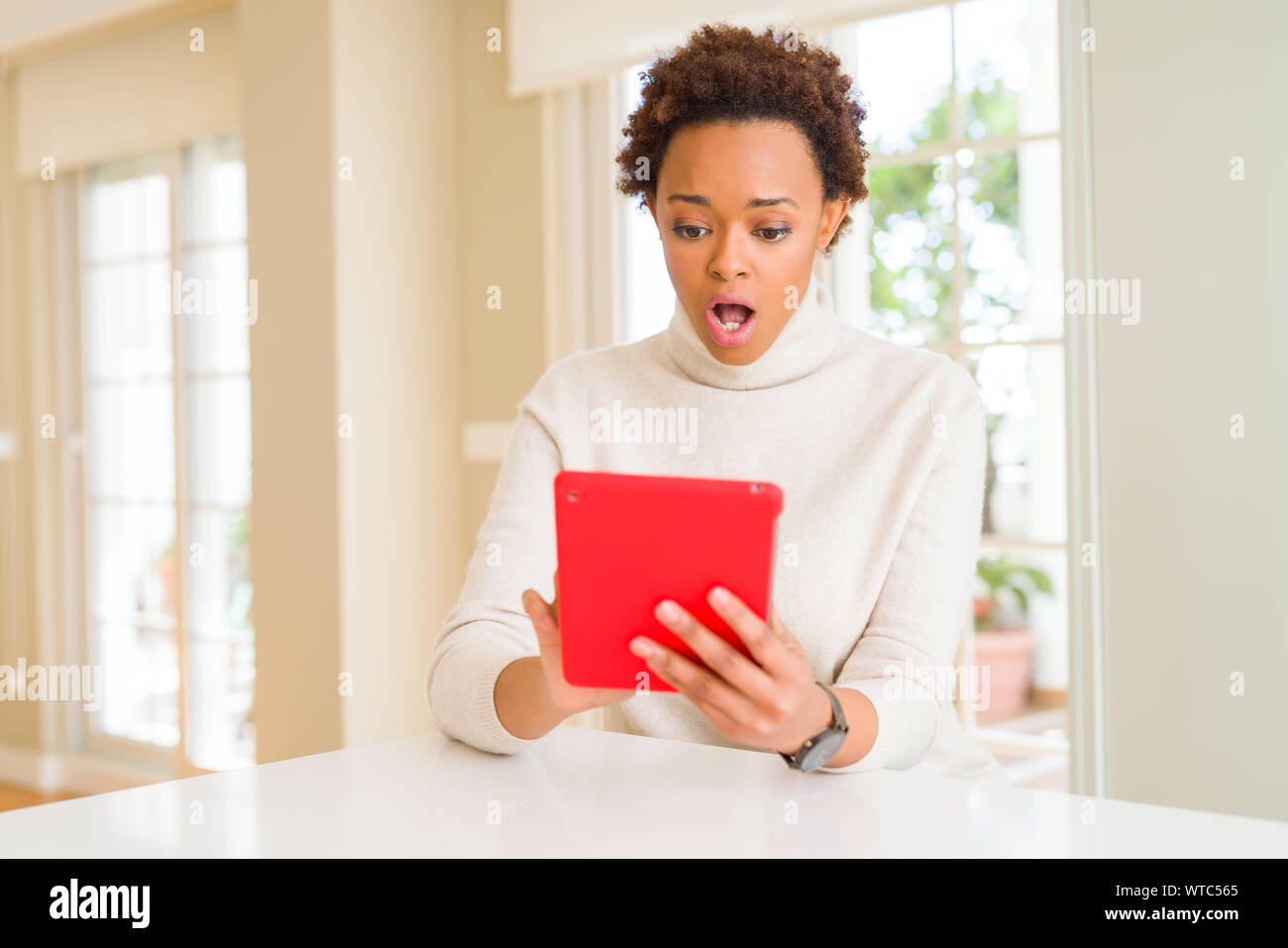 Young african american woman using tablet scared in shock with a ...