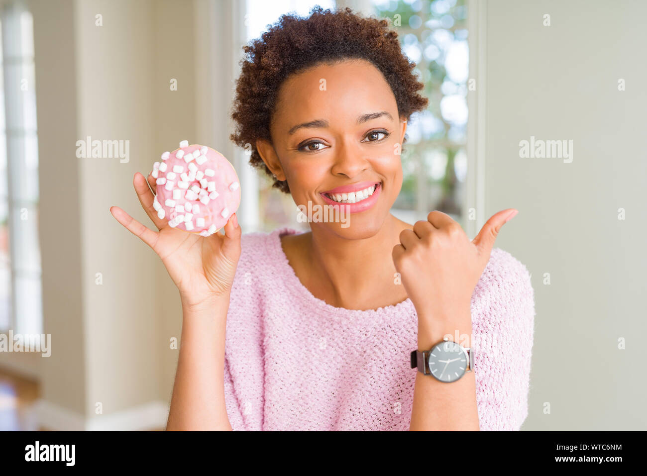 Young african american woman eating pink sugar marshmallows donut ...