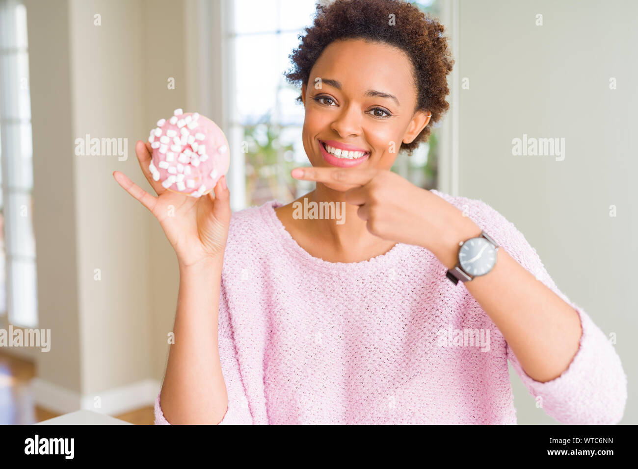 Young african american woman eating pink sugar marshmallows donut very ...