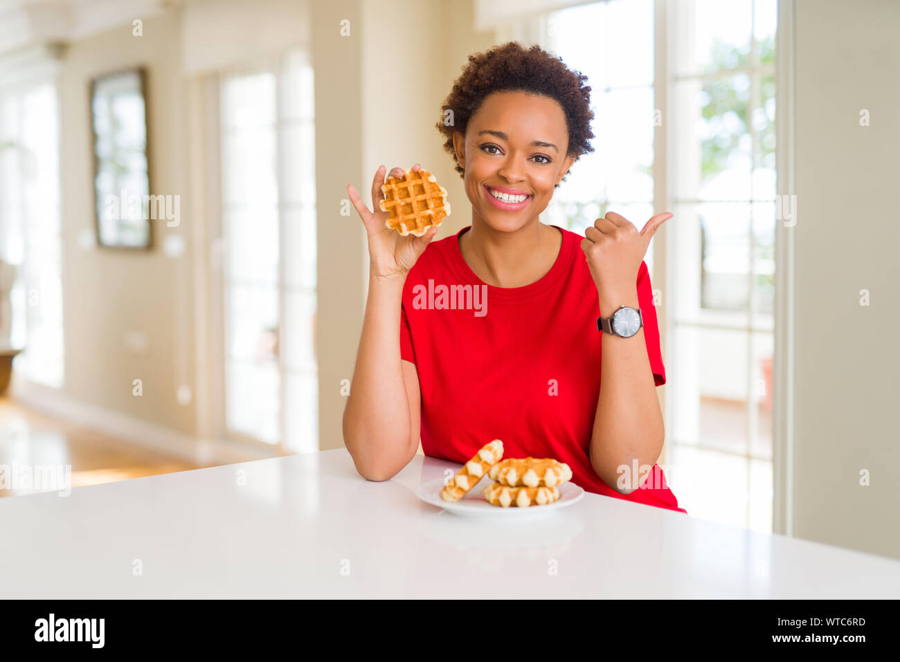 Young african american woman eating sweet waffle pointing and showing ...