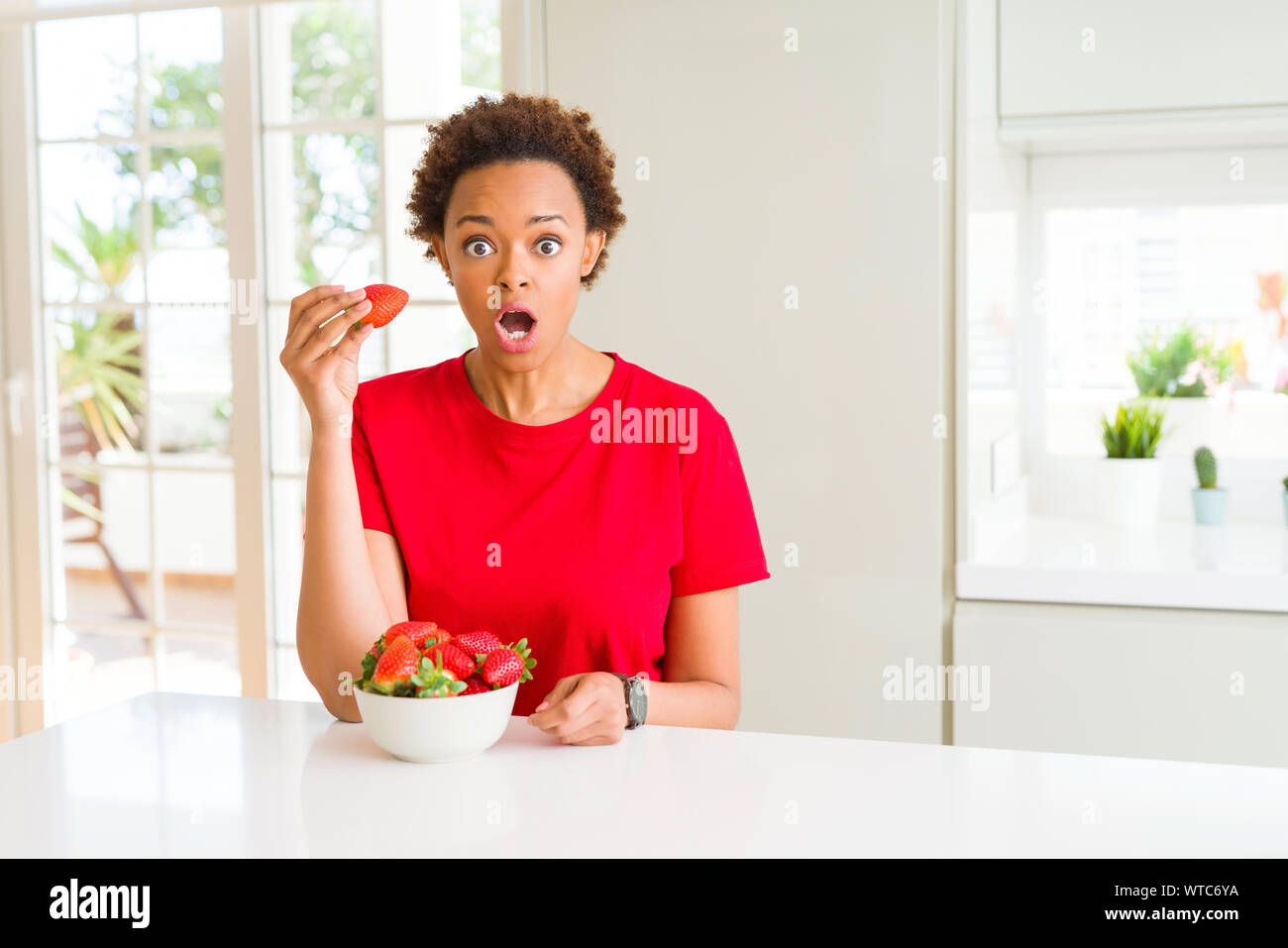 Young african american woman eating fresh strawberries for breakfast ...